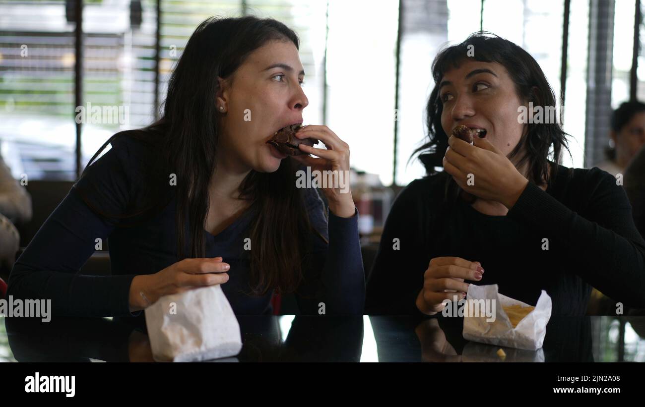 Two girlfriends eating burgers restaurant hi-res stock photography and ...