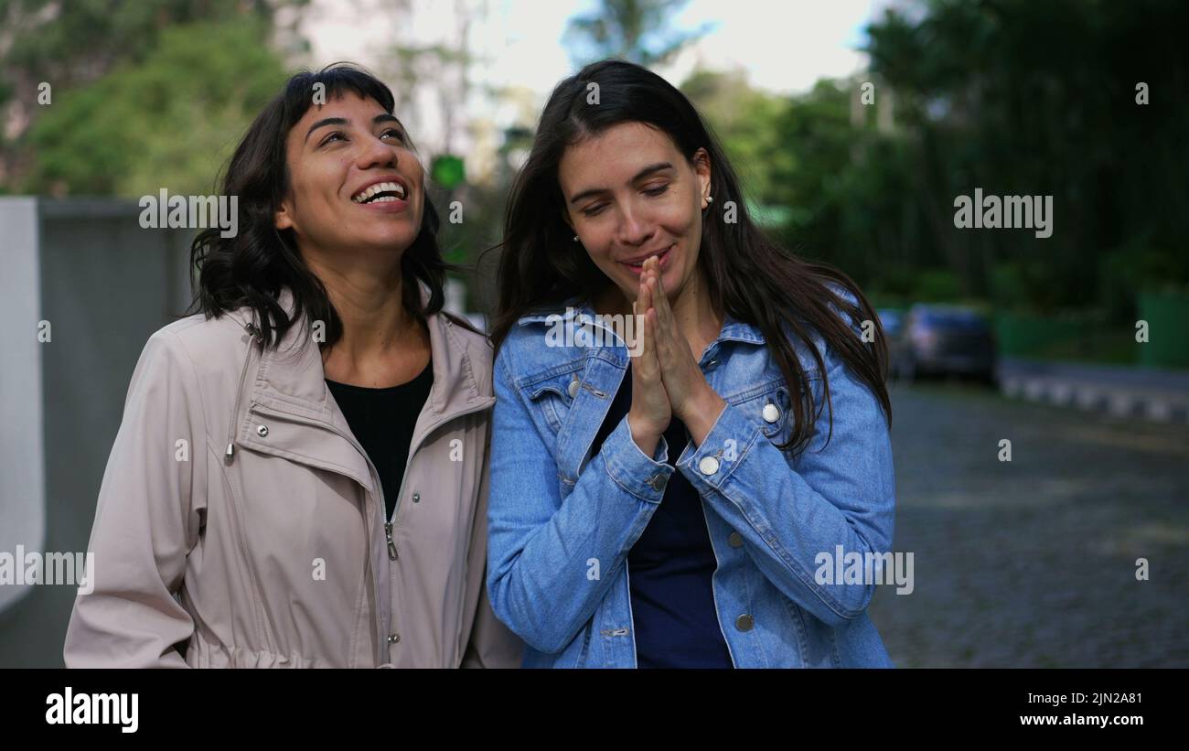 Two happy young women girlfriends walking outside laughing and smiling ...