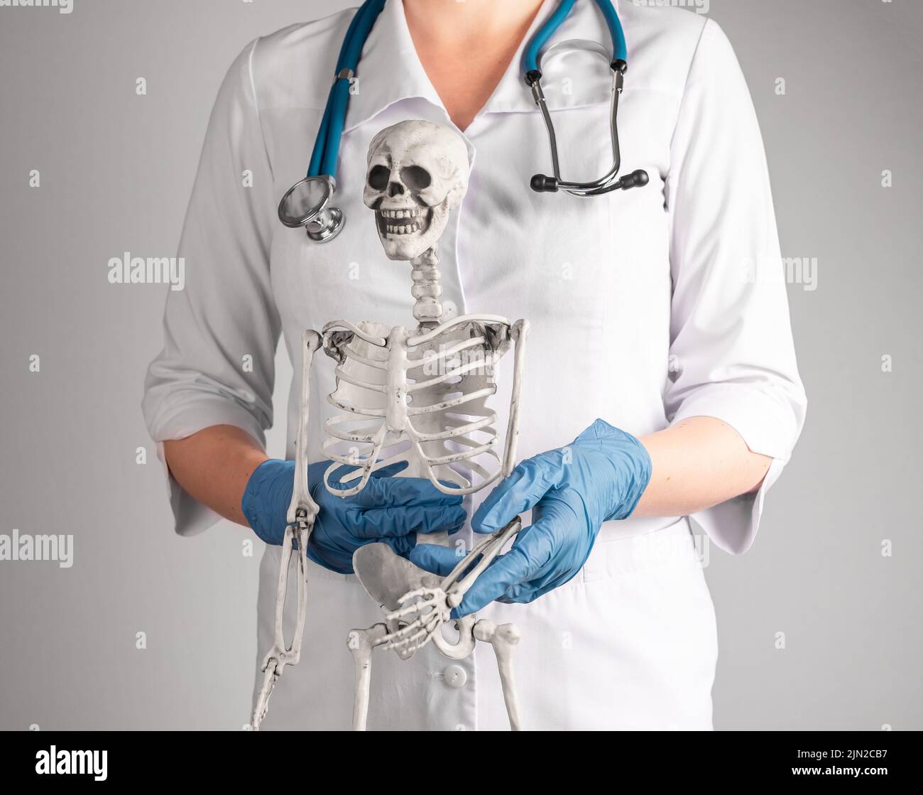 Doctor holding skeleton arm. Woman in lab coat with stethoscope ...