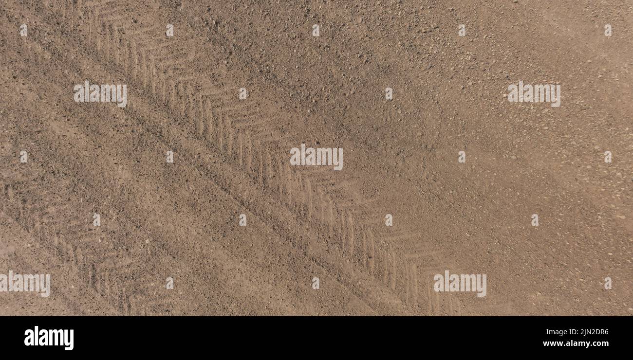 panorama of surface from above of gravel road with car tire tracks ...