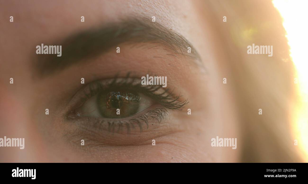 Macro close-up of young woman eyes in the sunlight with flare, opening ...