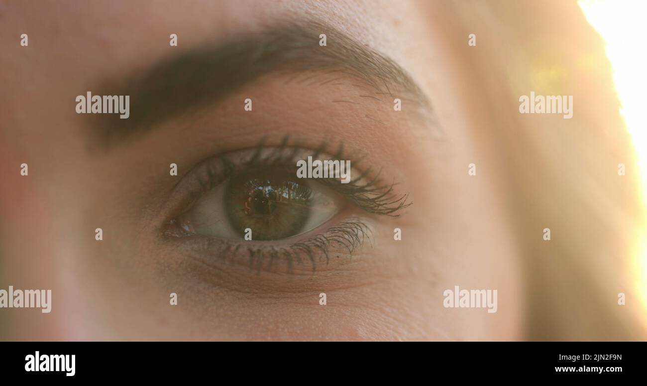 Macro close-up of young woman eyes in the sunlight with flare, opening ...