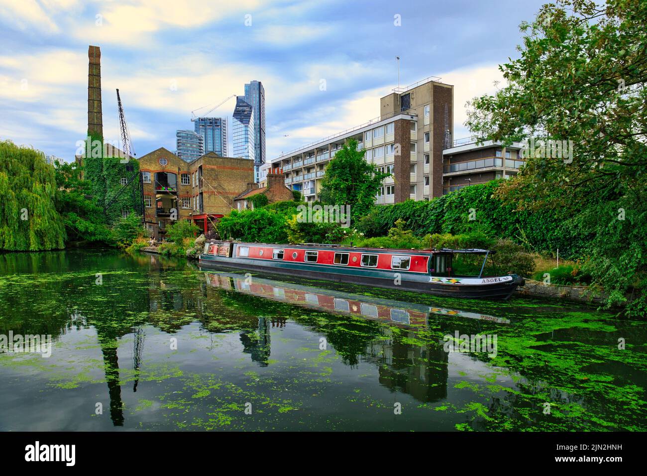 A narrowboat reflected in the tranquil water of Regent's Canal ...