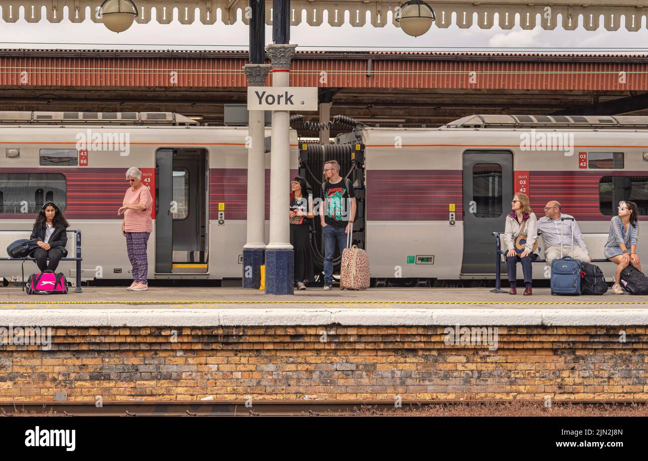 Passengers on a railway station platform look for an approaching train ...