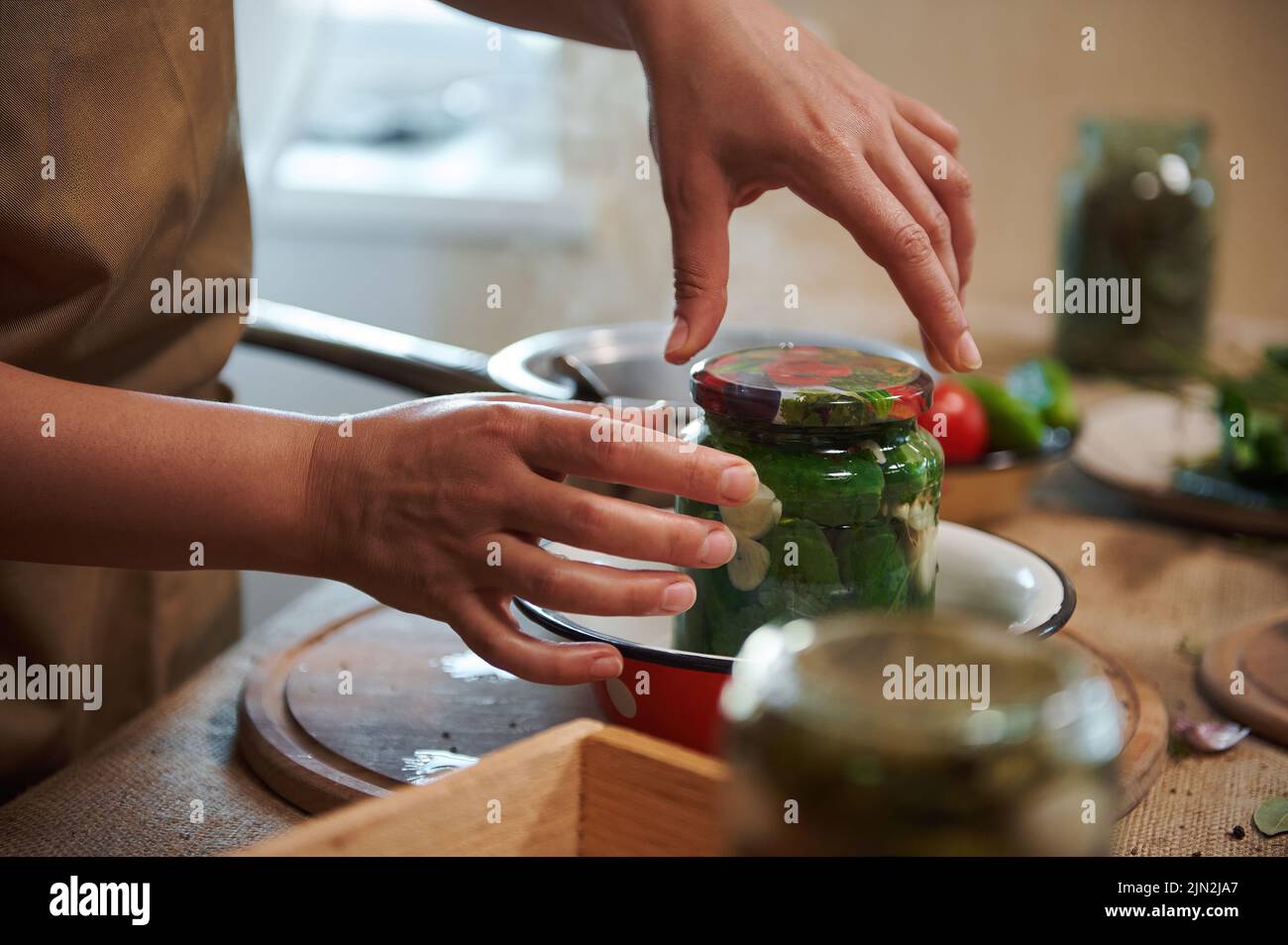 Details: housewife's hands covering with a sterilized lid a glass jar ...