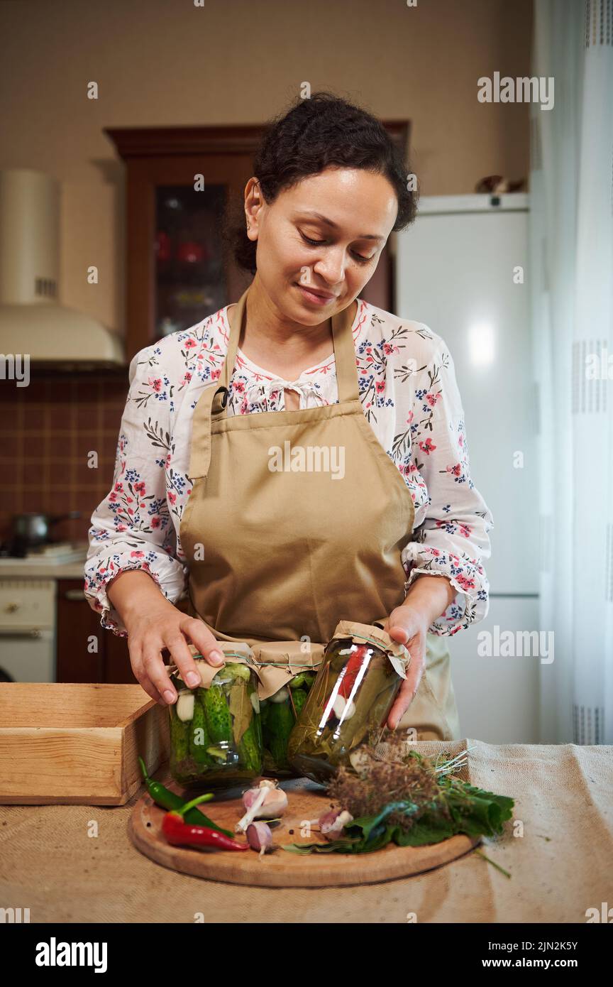 Pleasant woman, a housewife in beige chef's apron posing in her home ...