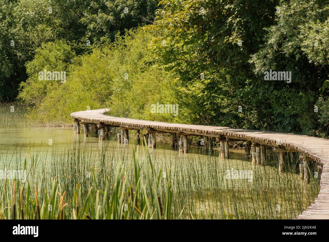 Long wooden footbridge over lake for tourists. Idyllic lake surface ...