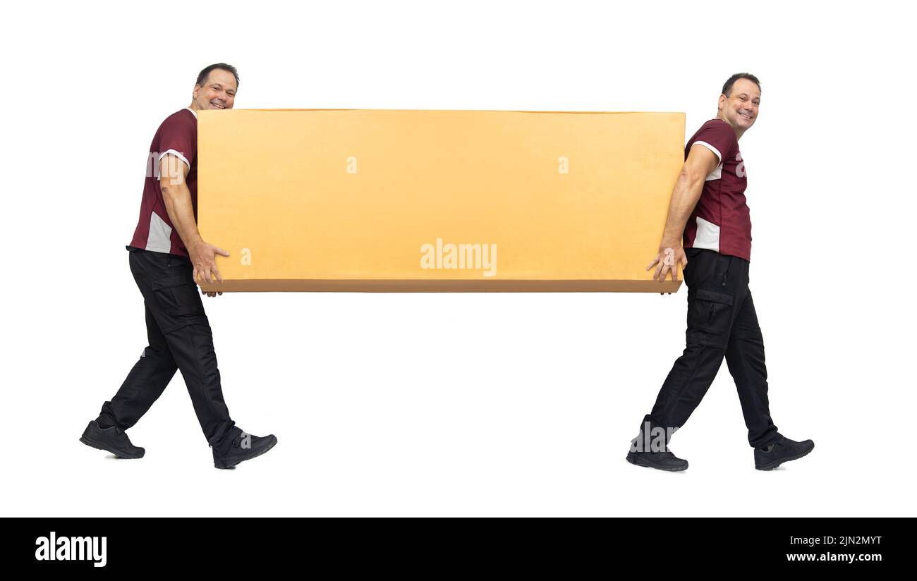 Two smiling men carry a large package, isolated on white background ...