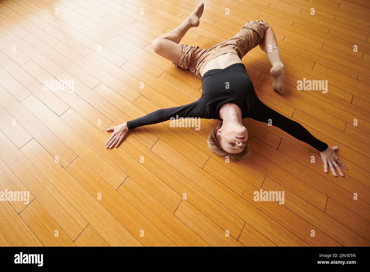 Slim female dancer performing contemporary dance on parquet floor Stock ...