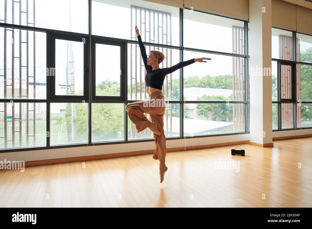 Talented young woman dancing to music in spacious studio Stock Photo ...