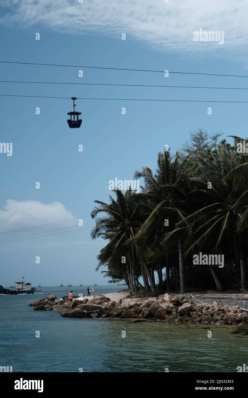 A vertical shot of a cable car above palms on the beach in Jakarta Bay ...