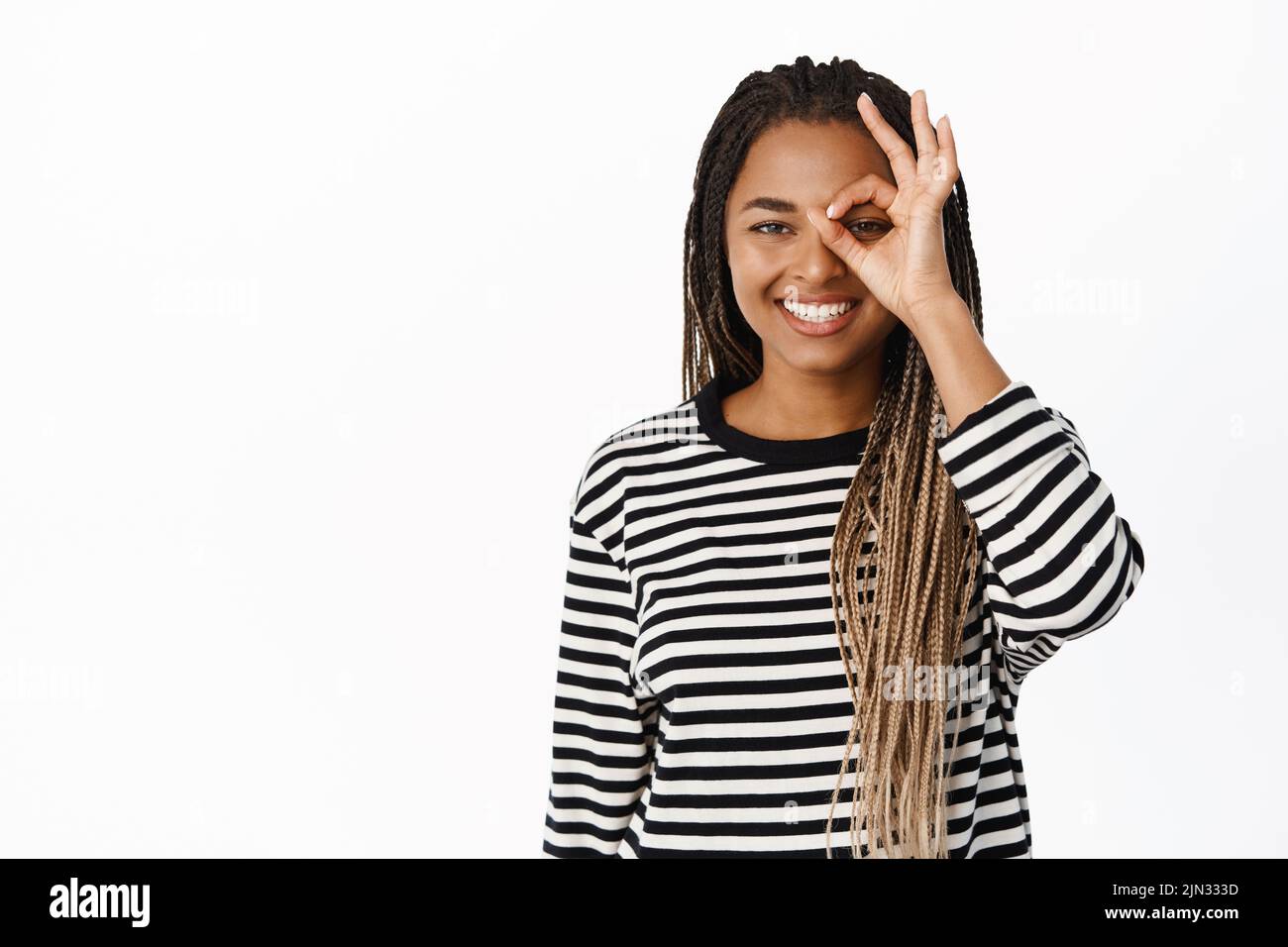 Portrait of smiling african woman shows okay, zero gesture on eye ...