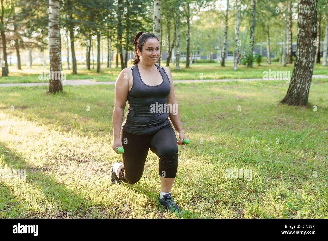 A charming brunette woman plus-size body positive practices sports in ...
