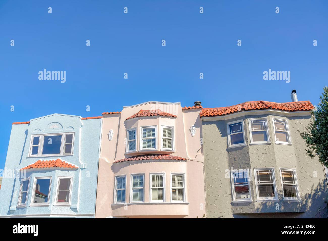 Three adjacent houses with clay roof tiles against the blue sky at San ...
