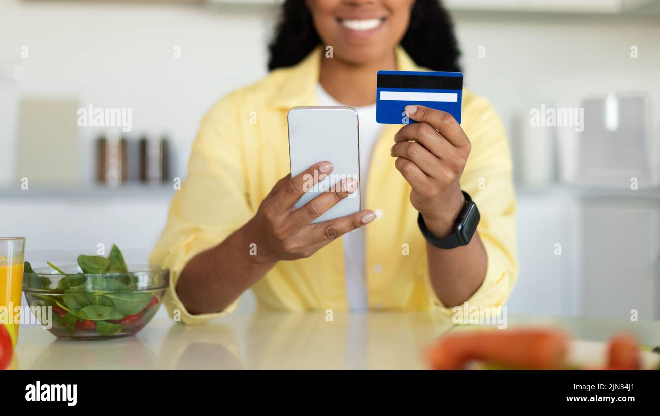 Grocery delivery app. Young black woman using cellphone and credit card ...