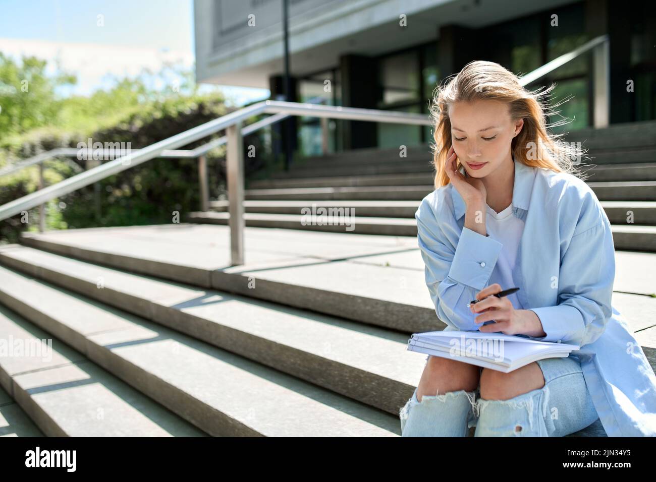 Pretty girl college student holding notebook sitting on stairs outside ...