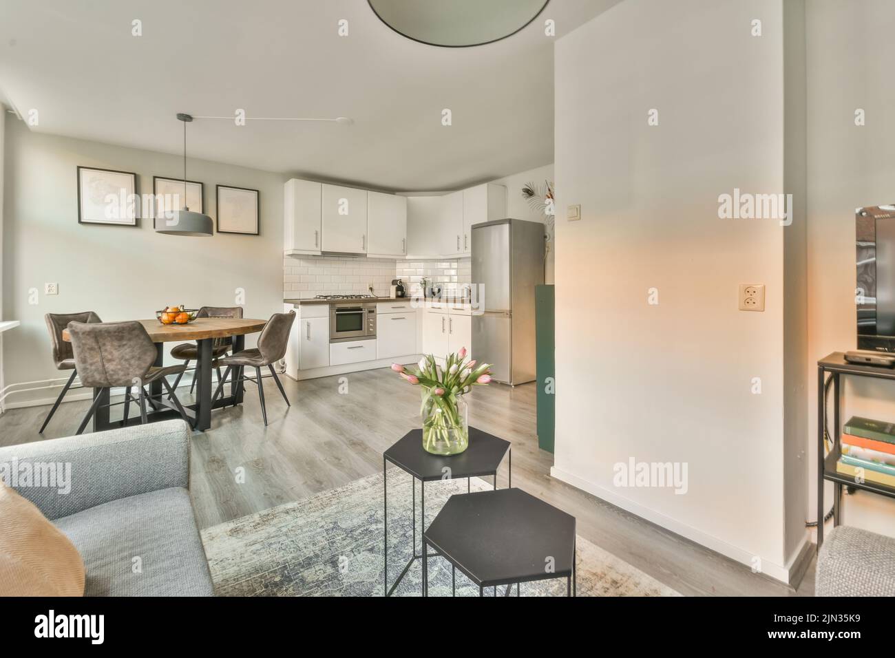 Table with chairs and flowers located near lounge area and kitchen in ...