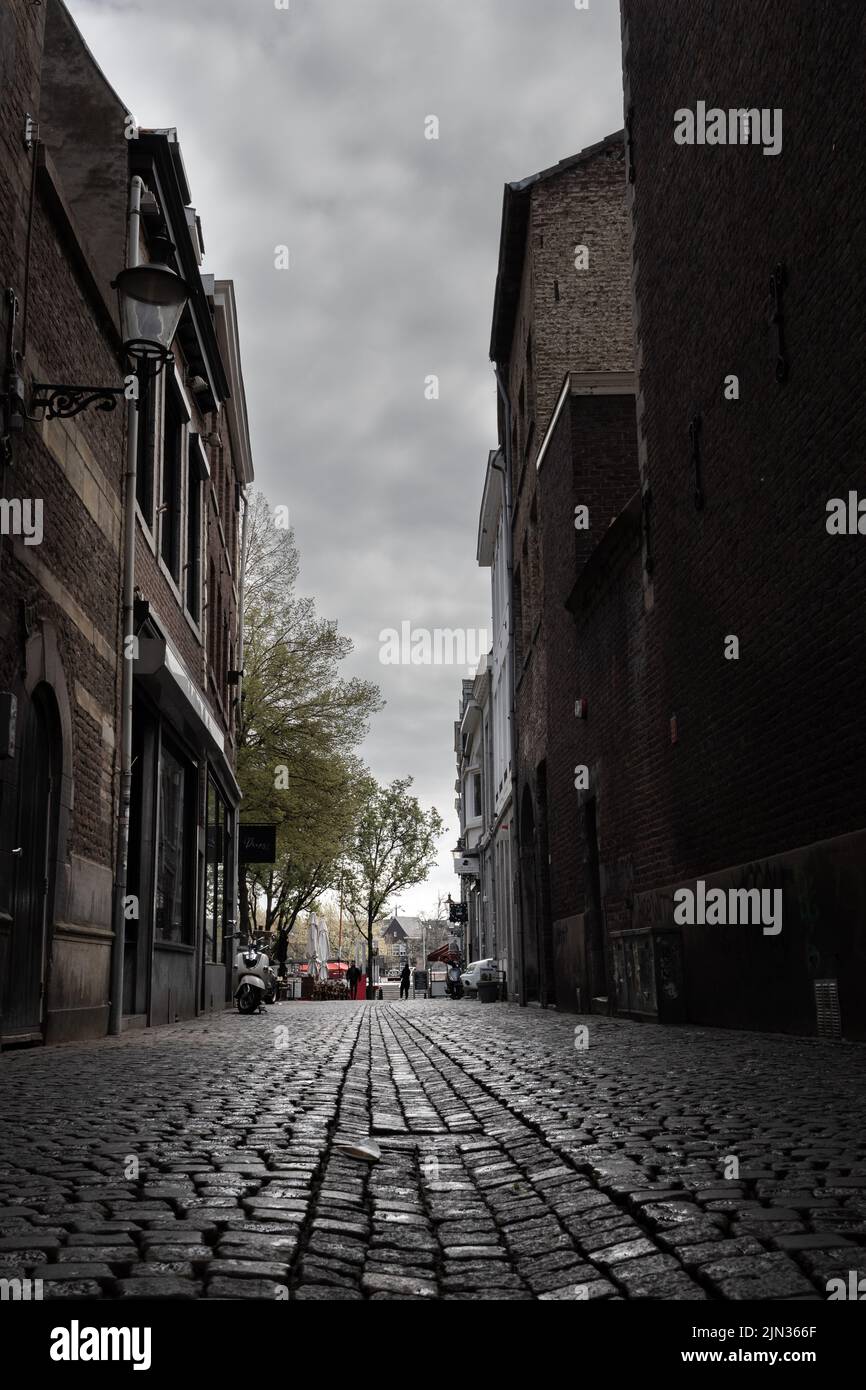 A vertical shot of a narrow pebble road between buildings on a cloudy ...