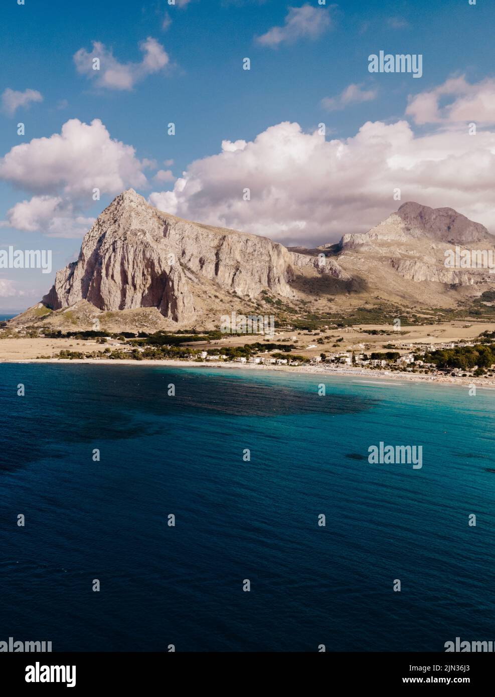 A vertical shot of an azure sea against rocky mountains background in ...