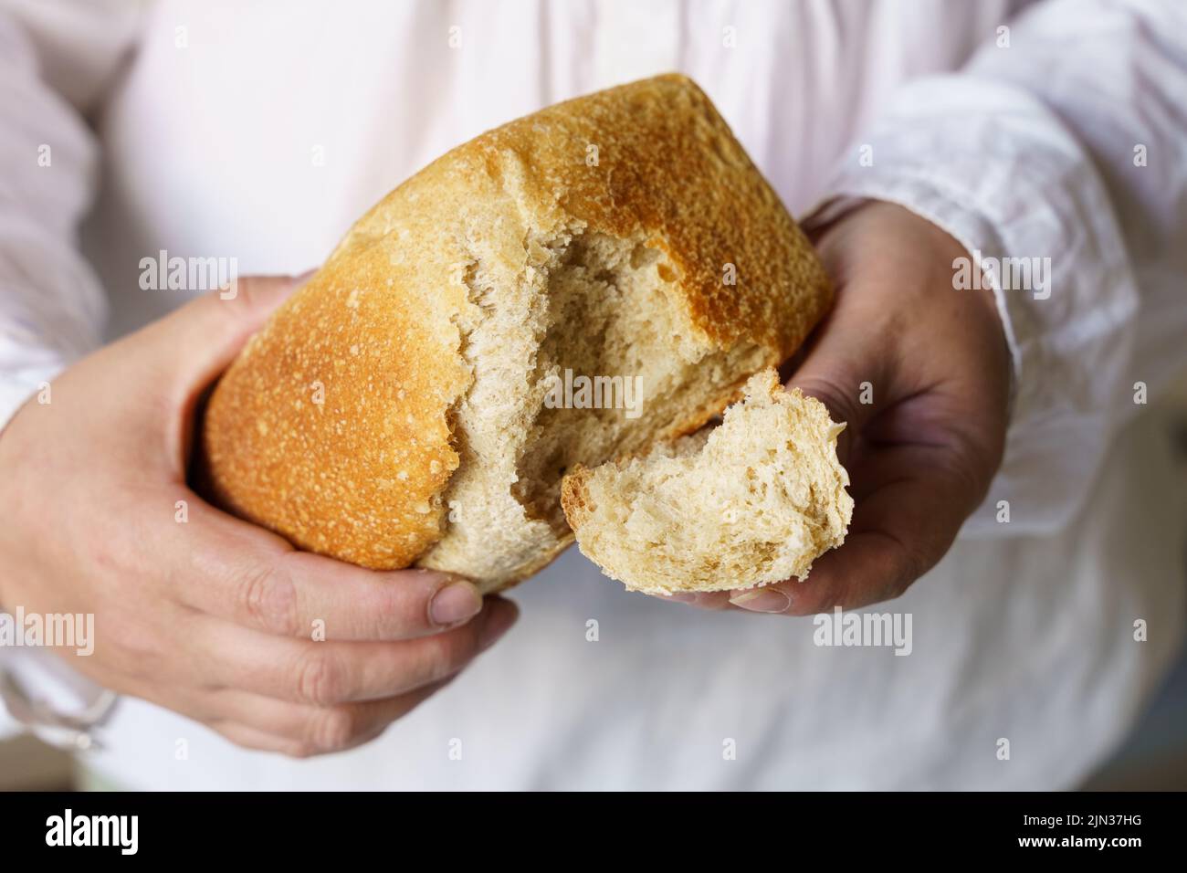 A man holds cooked bread in his hands, tears off a piece from it. Food ...