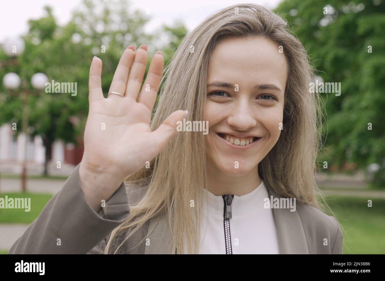 The woman smiles and waves her hand. Portrait of a beautiful woman ...