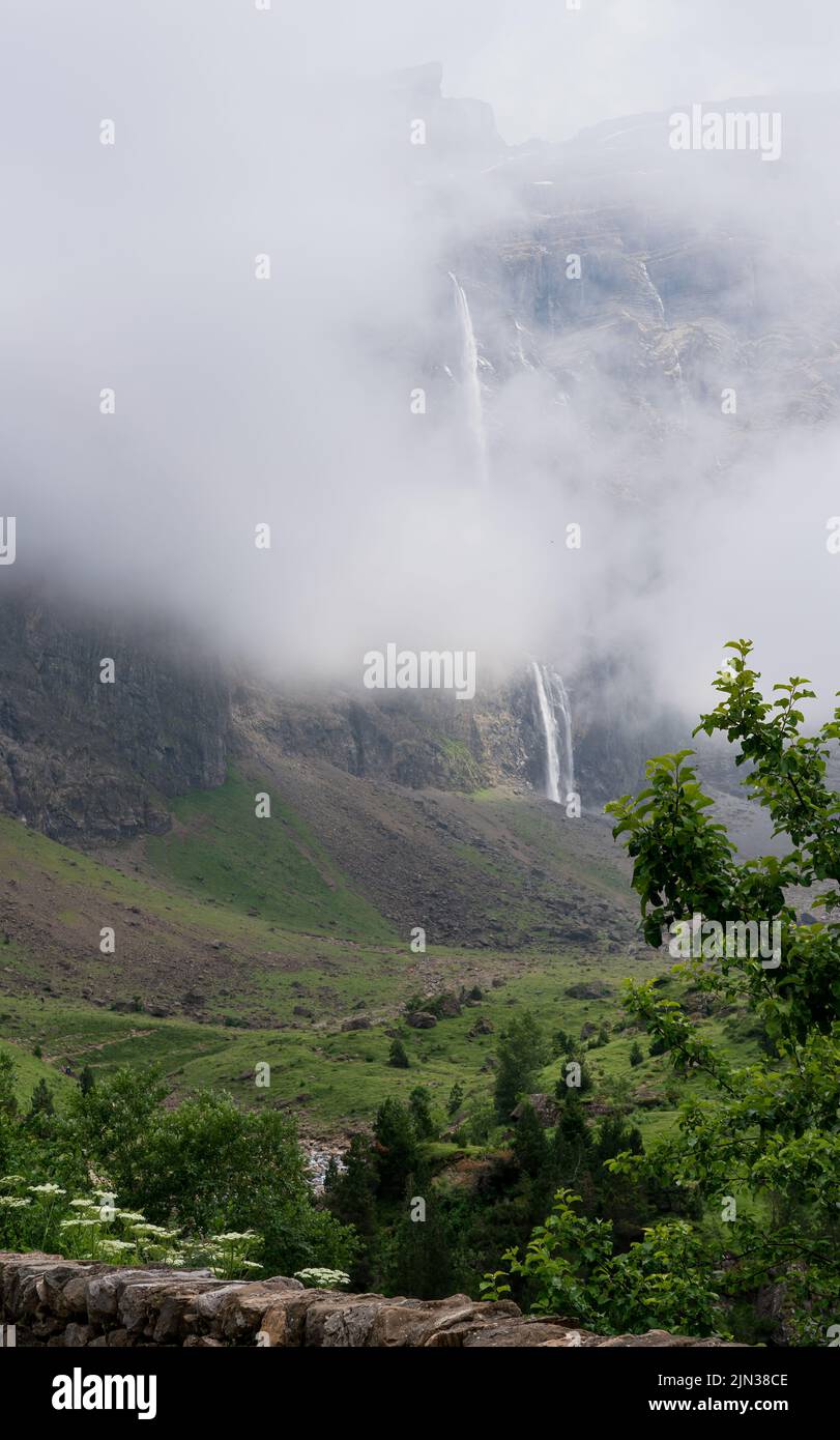 large waterfalls on steep mountain cliffs, low cloud in the valley ...