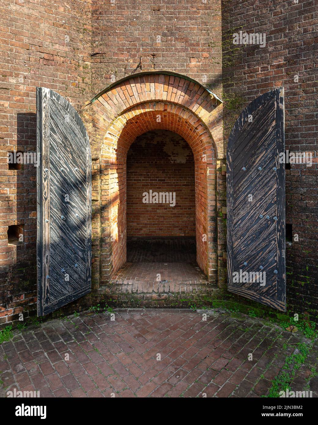 Arched brick doorway with black wooden open doors. Plenty of texture ...