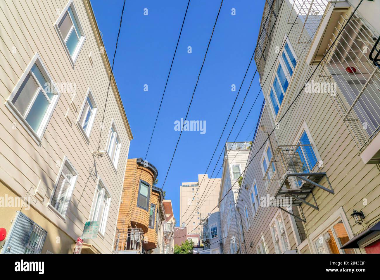 Electrical wires in the middle of rows of houses in a low angle view at ...