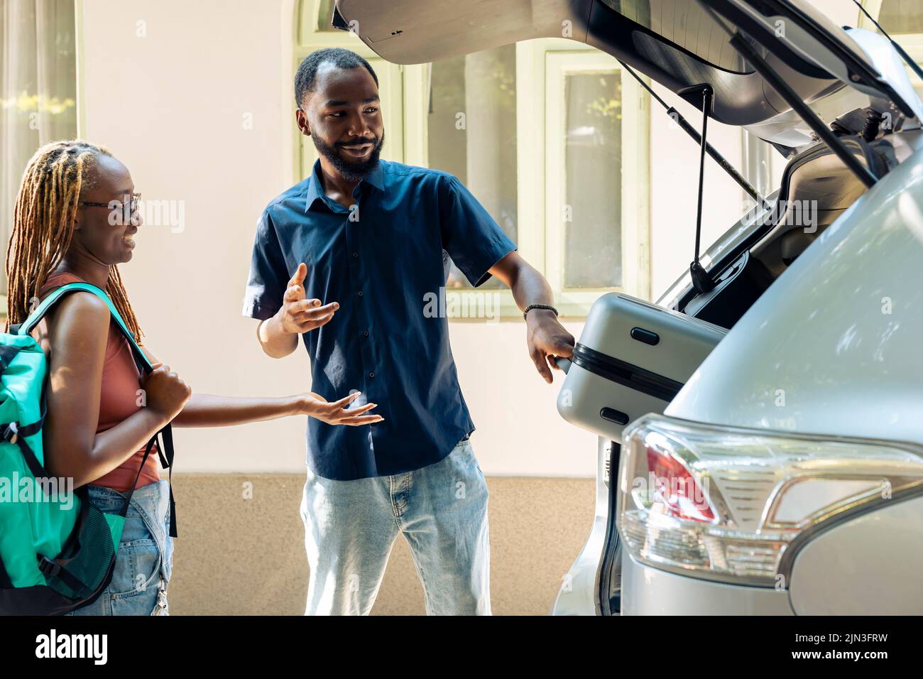 Happy people loading baggage in car trunk, travelling on summer ...
