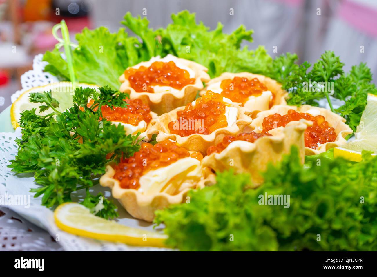 Red caviar and grated cheese in small dough baskets. A delicious cold ...