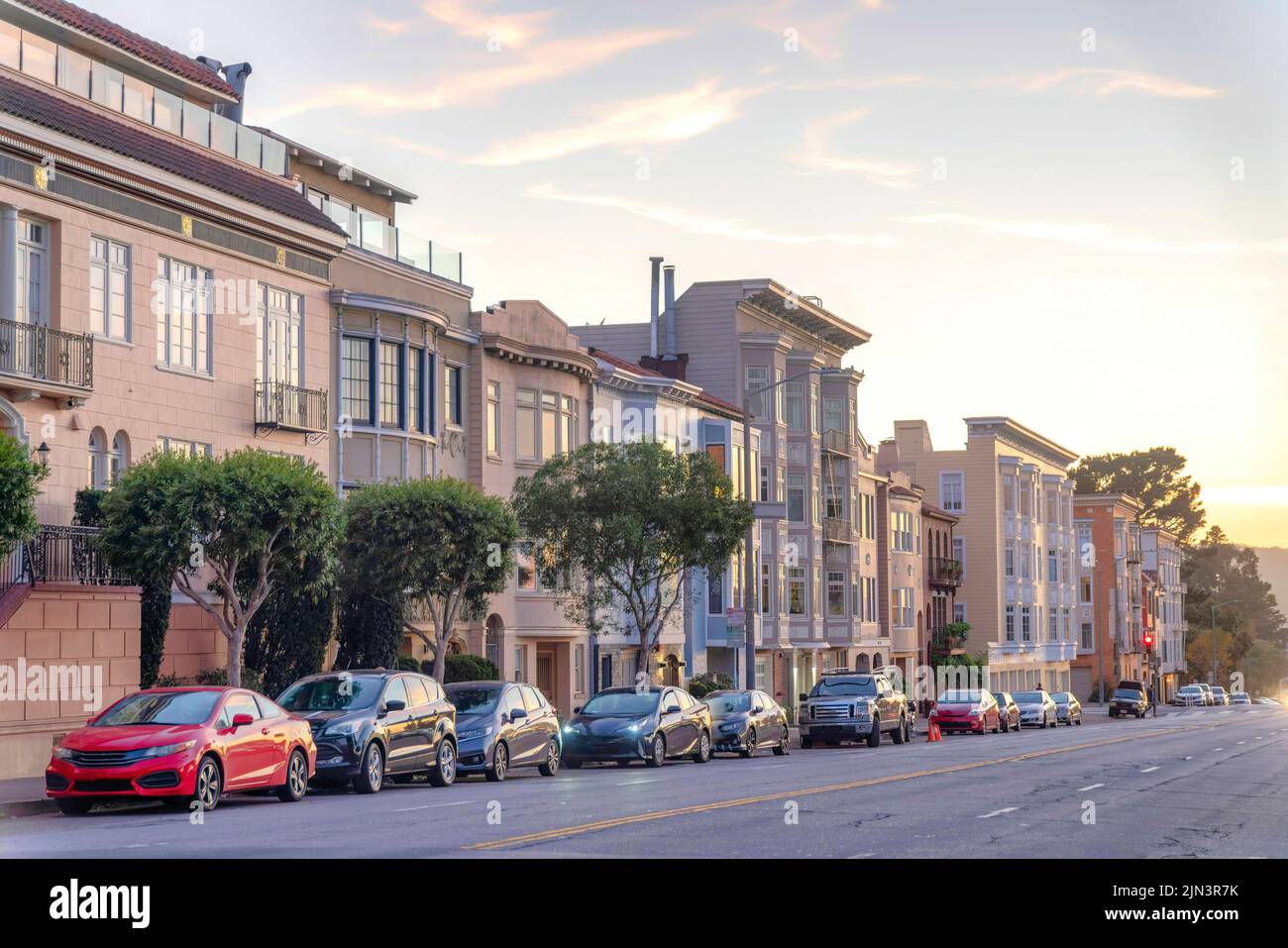 Road with parked vehicles at the front of residential buildings in San ...