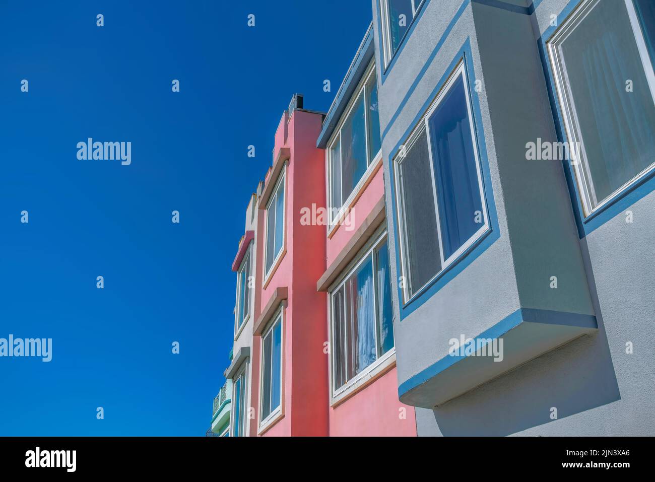 Low angle view of residential buildings with pink and blue stucco walls ...