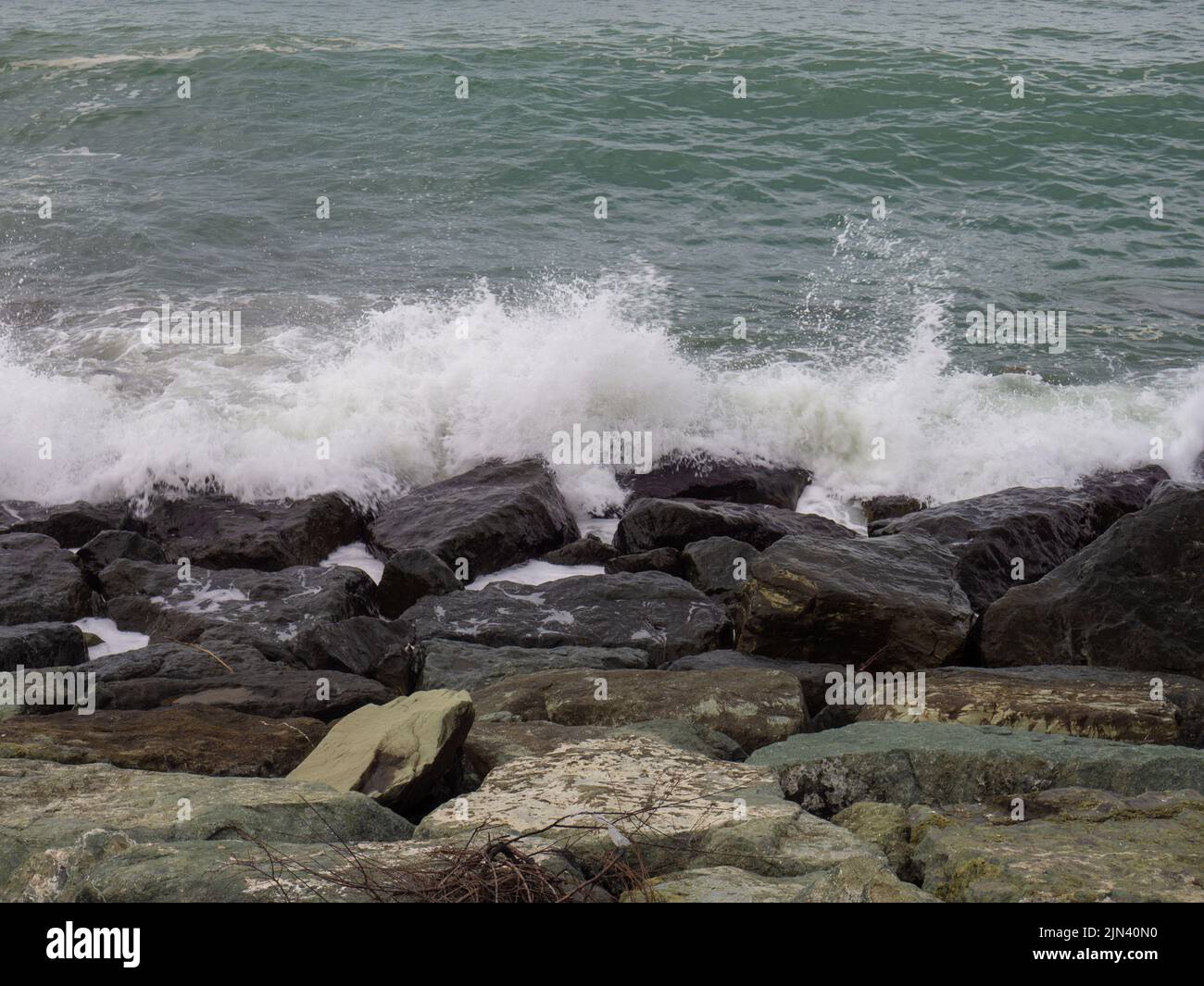 Rocky seashore. The shore is fortified with huge stones. Large waves on ...