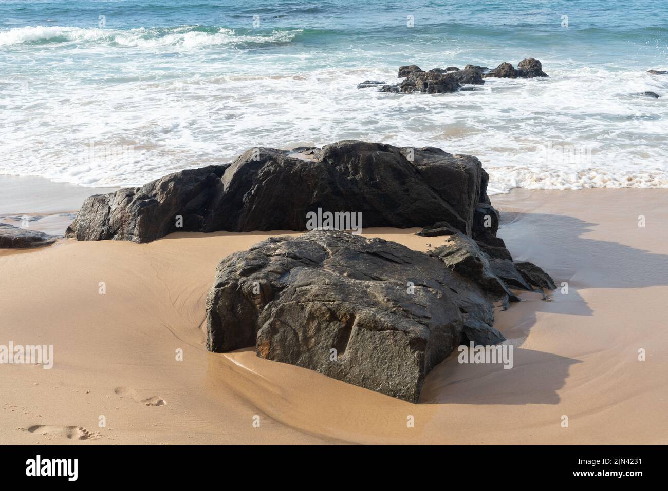 A wave breaks about a rock during a curtain on the sea. Farol da Barra ...