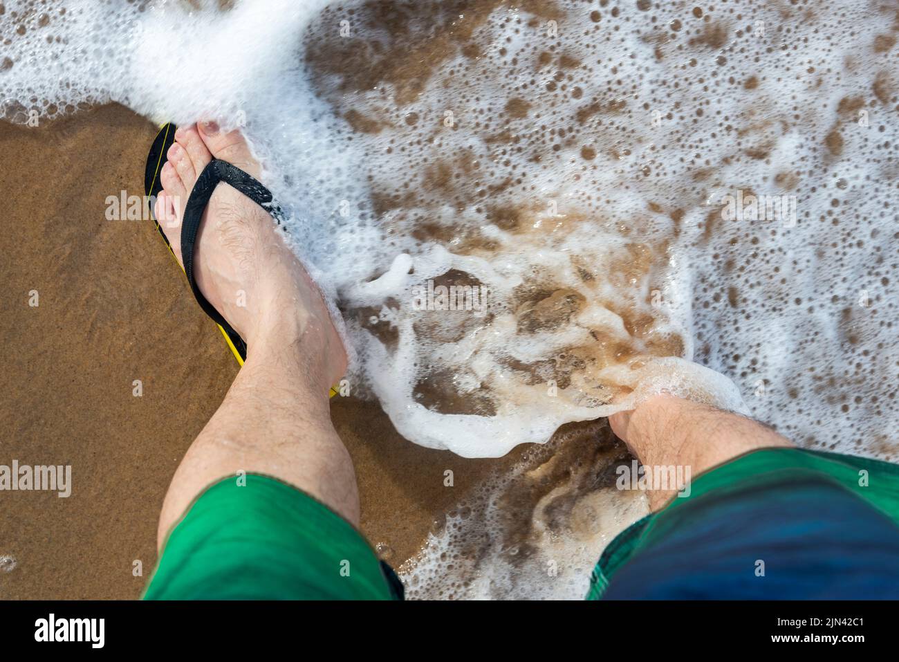 Top to bottom view of feet on the beach sand. Barra beach lighthouse ...