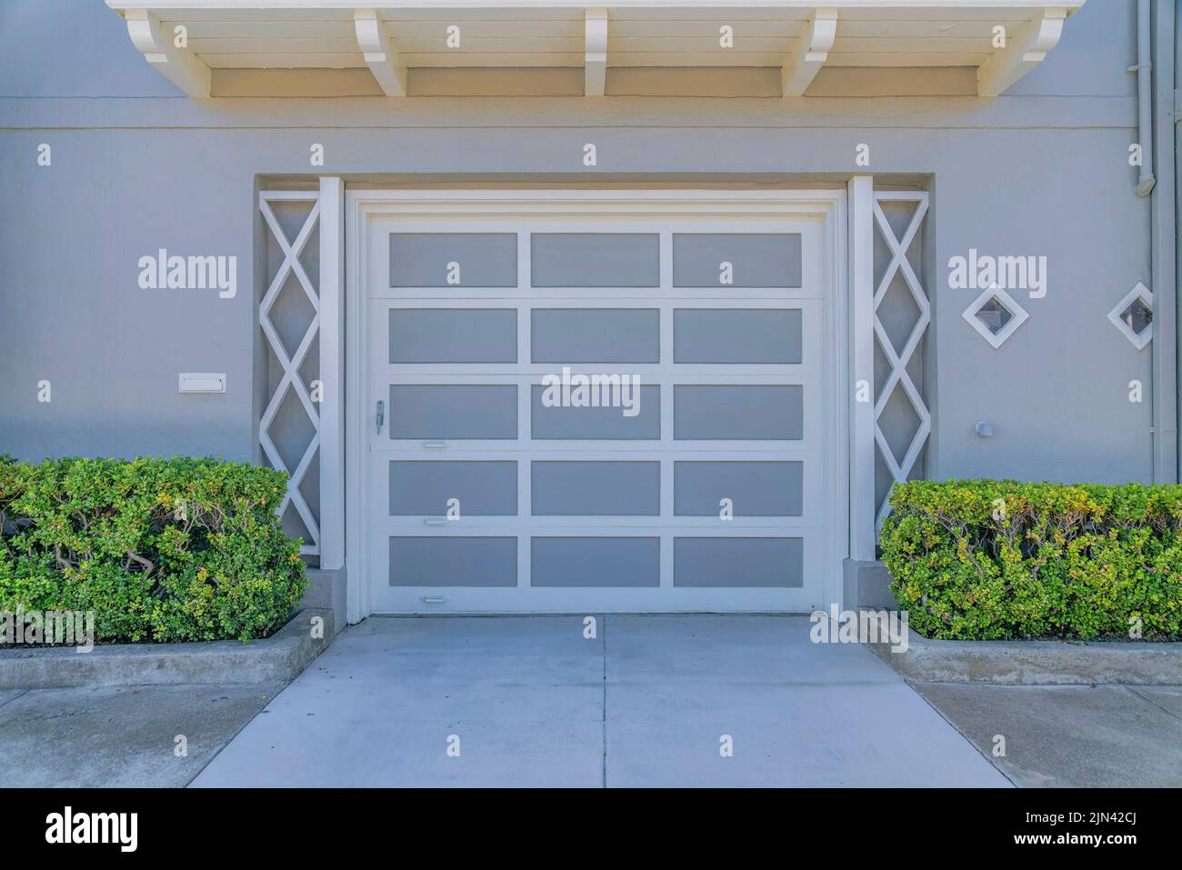 Garage exterior with bushes on the side near the gray walls- San ...