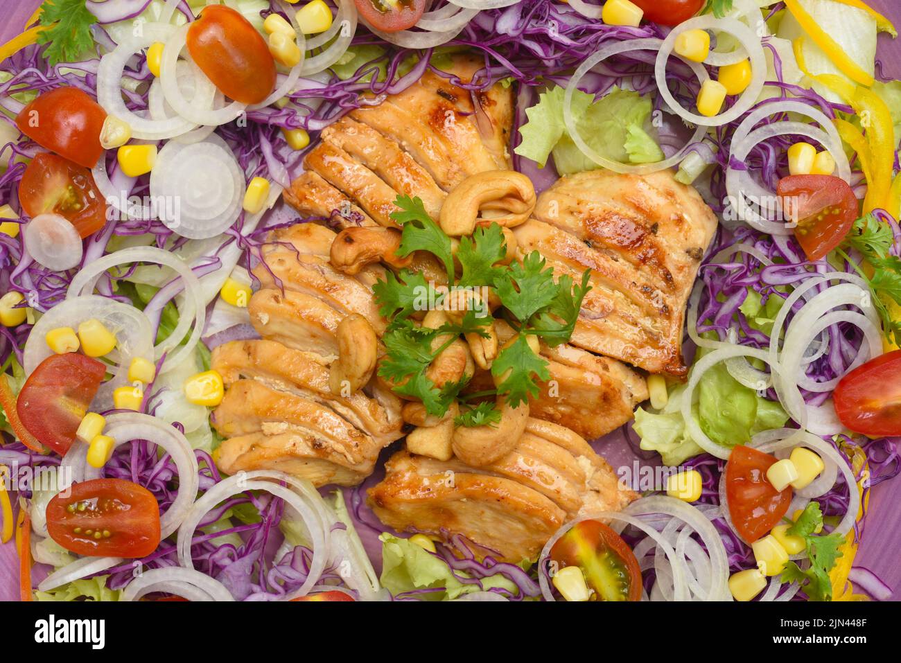 Pan fried chicken on a purple plate with greens and mulberry sauce on ...