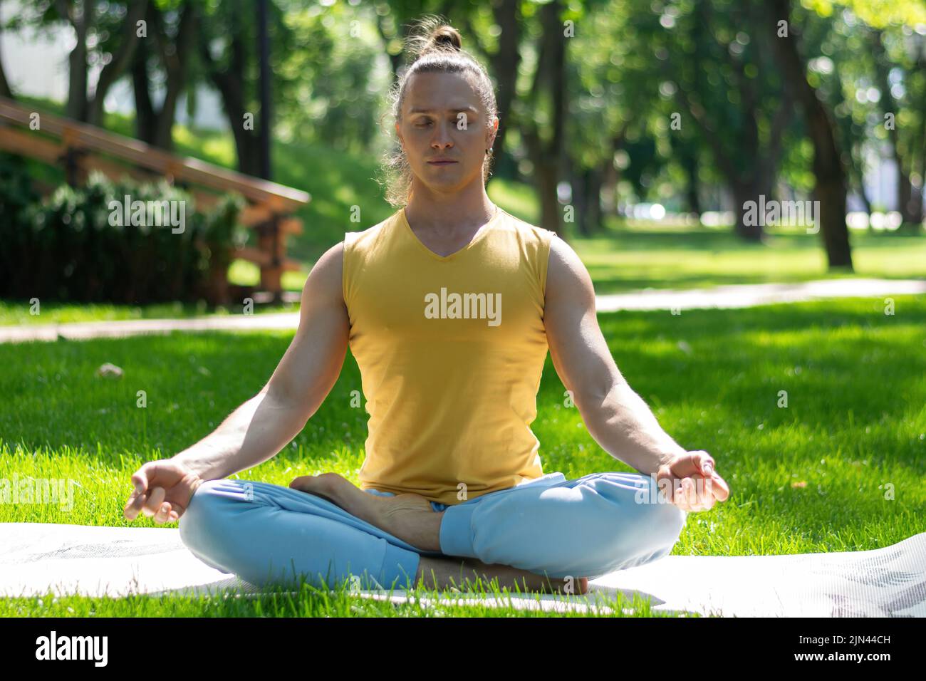 Young man practice yoga in the park. Yoga asanas in city park, sunny ...