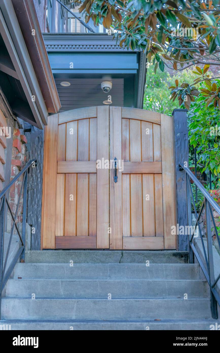 Arched wooden double gate entrance with concrete stairs and security ...