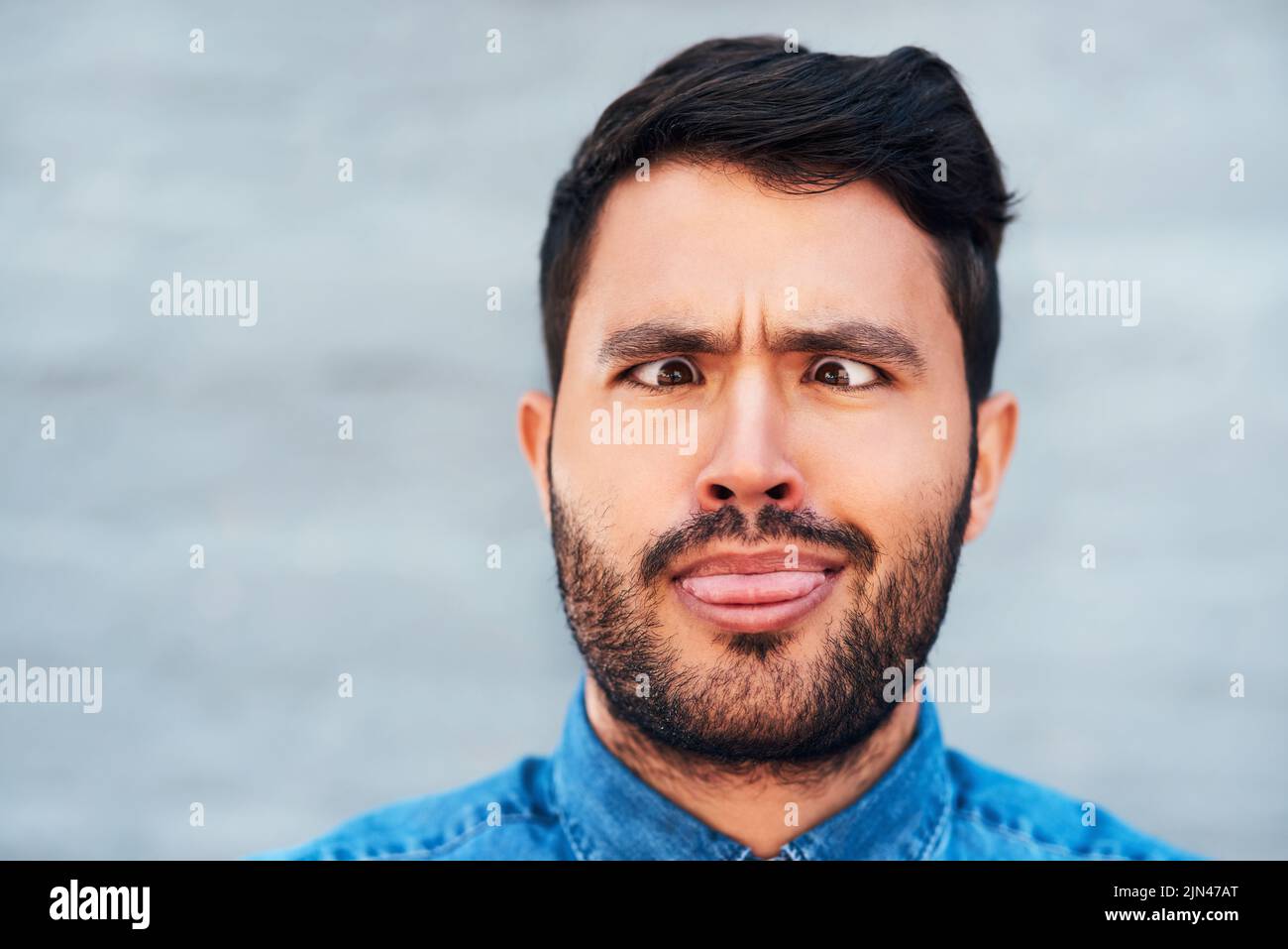 Silly isnt he. a handsome young man making funny faces while standing ...