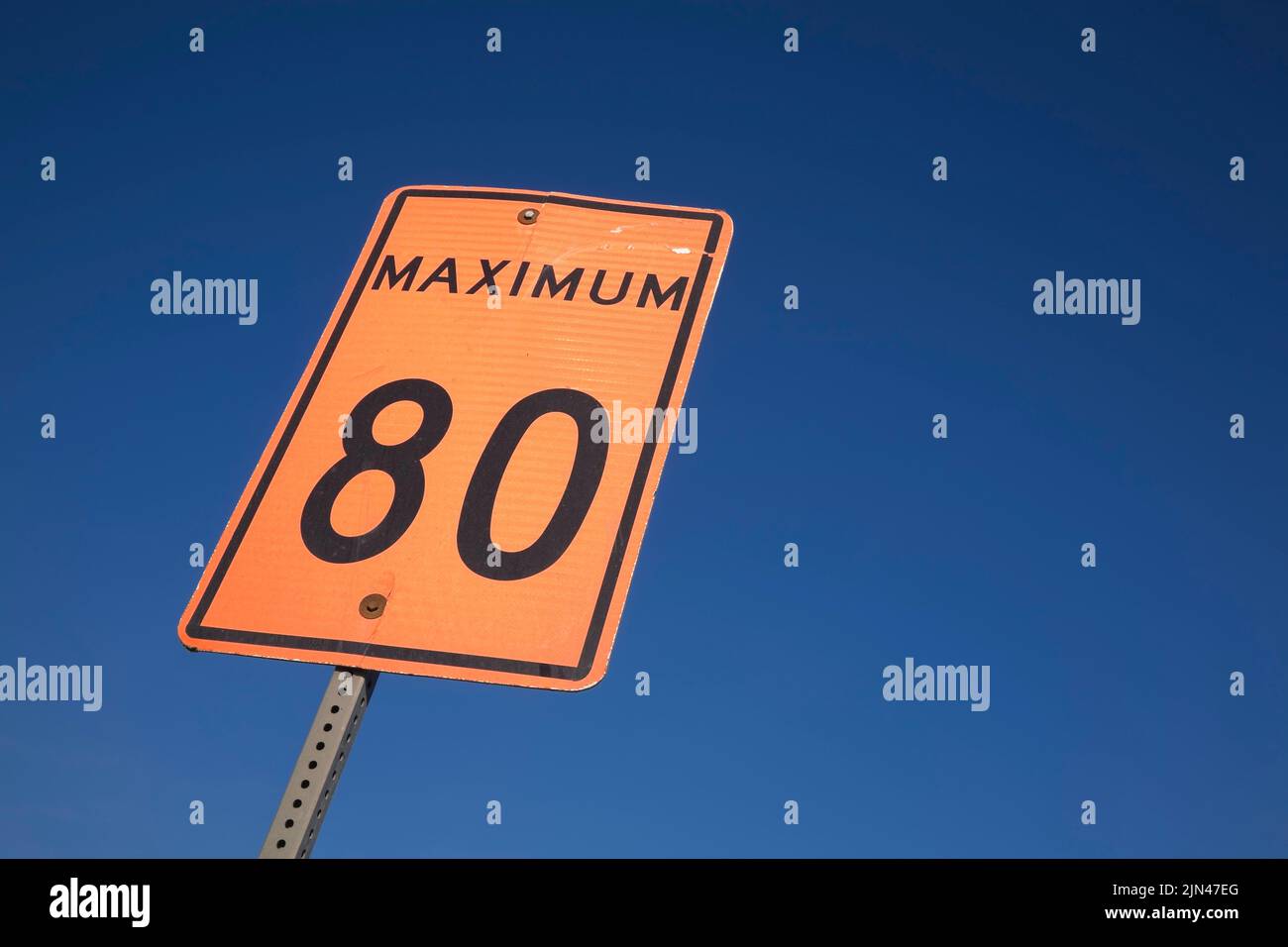 Orange 80 maximum speed limit traffic sign against a blue sky ...