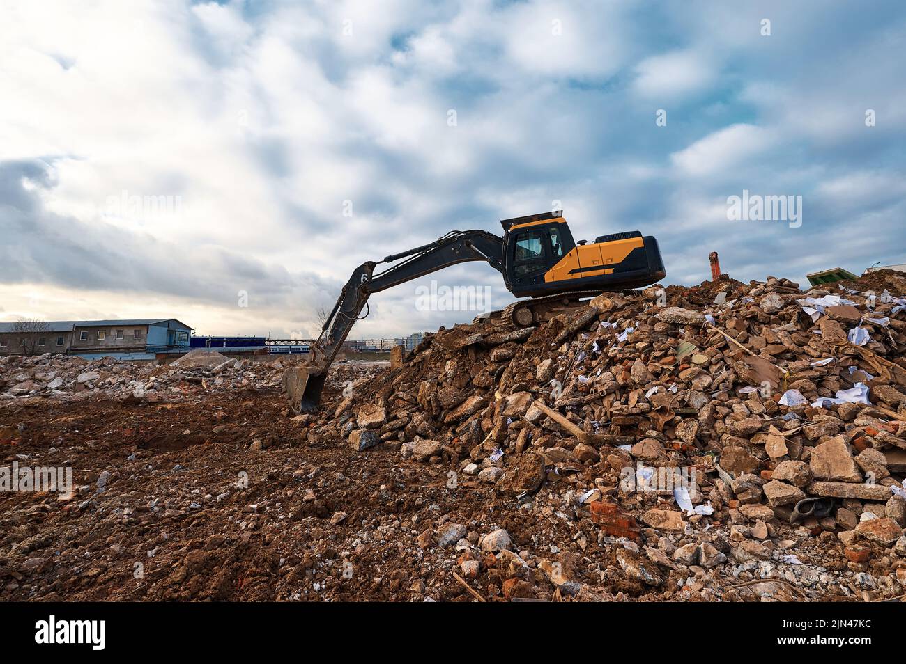 Excavator pours soil on pile of garbage at demolition site Stock Photo ...