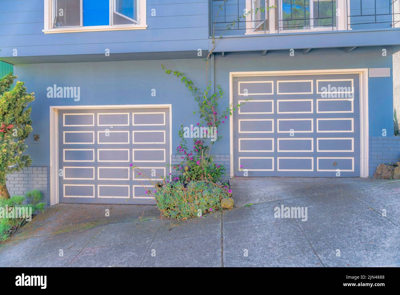 Attached garage of townhomes with identical garage doors on a sloped ...