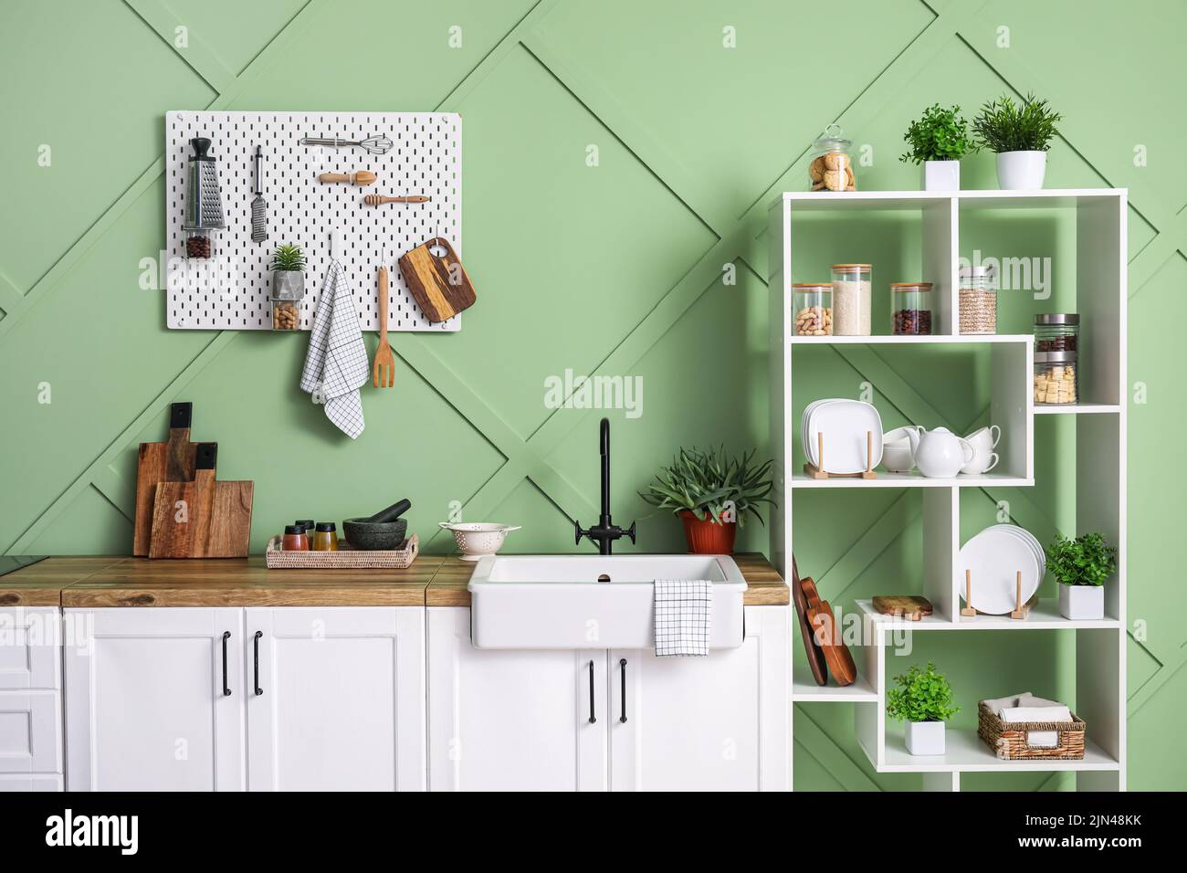 Interior of stylish kitchen with white counters, pegboard and shelving ...