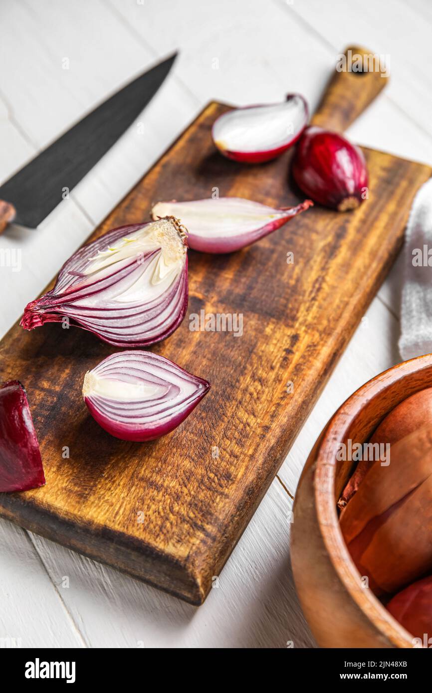 Board with cut red onion on light wooden background, closeup Stock ...