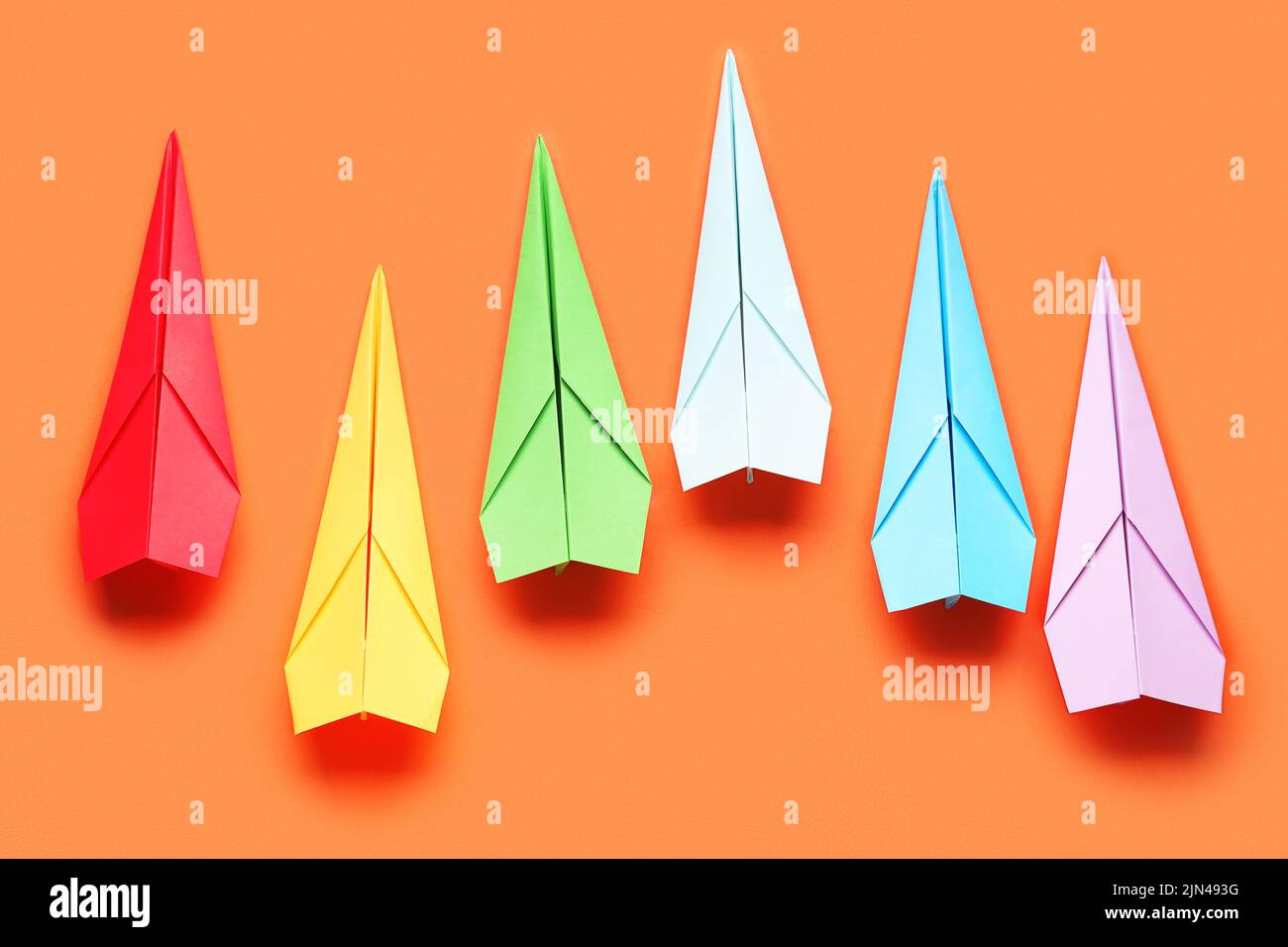 Colorful paper planes on orange background Stock Photo - Alamy