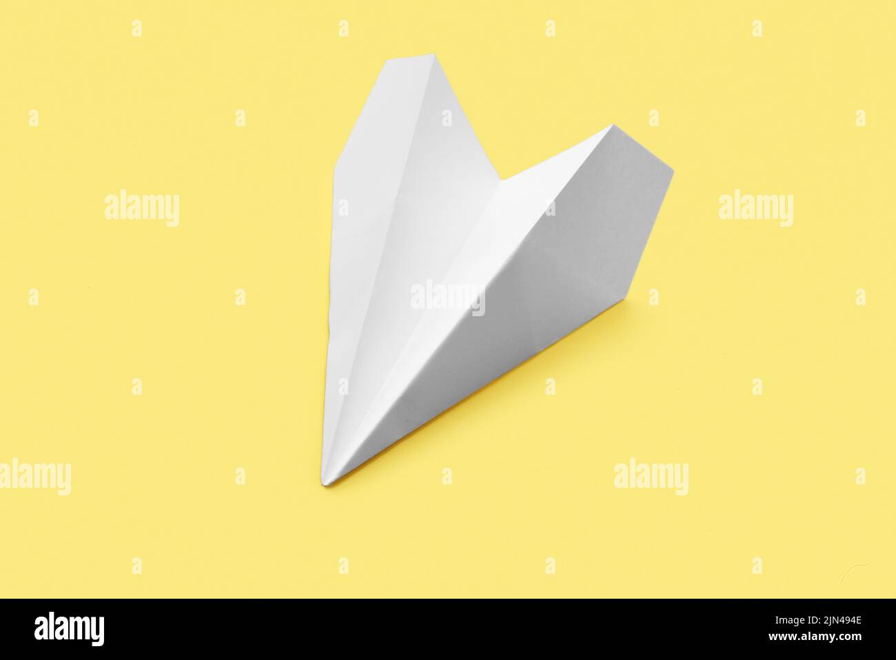 White paper plane on yellow background Stock Photo - Alamy