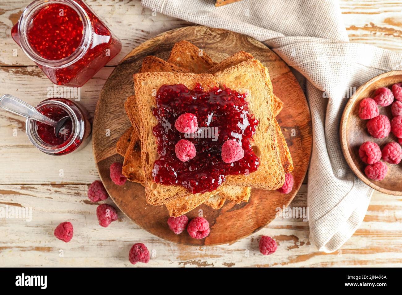 Plate with tasty toasts and raspberry jam on white wooden background ...