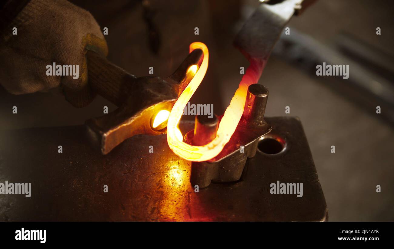 Blacksmith bending a longer piece of hot metal in a knife handle Stock ...