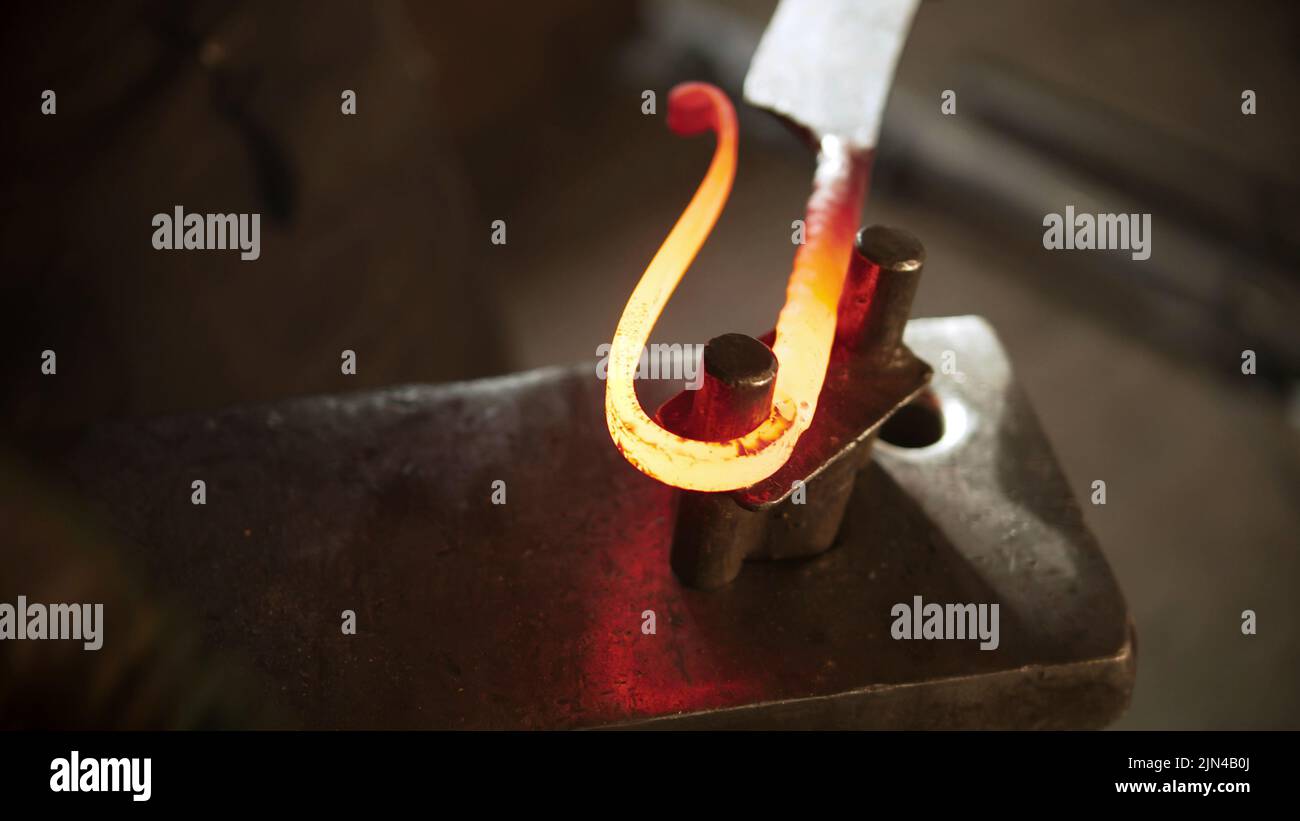 Blacksmith bending a piece of hot metal in a knife handle Stock Photo ...